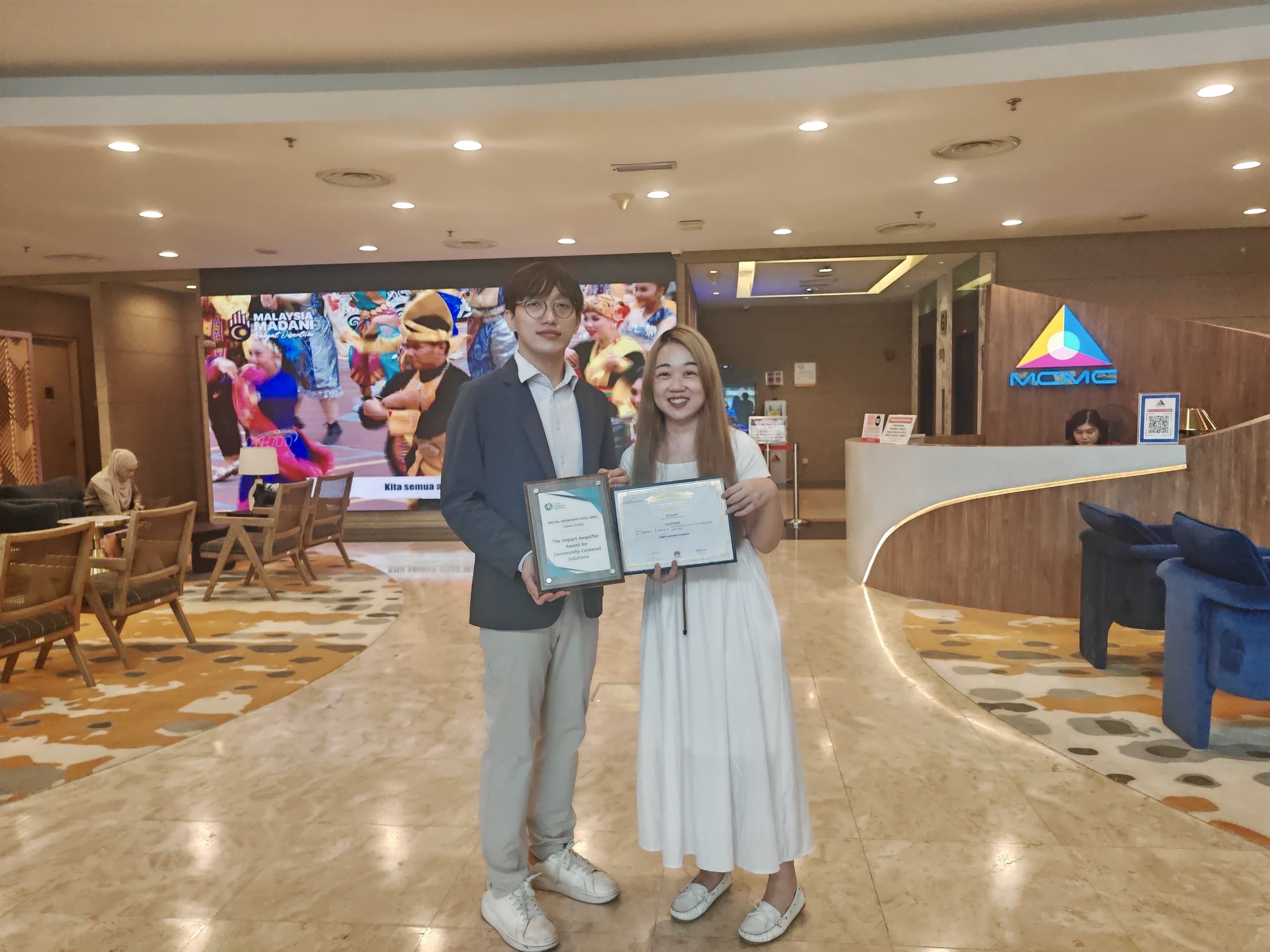 Dr Aun (left) displaying his award at MCMC